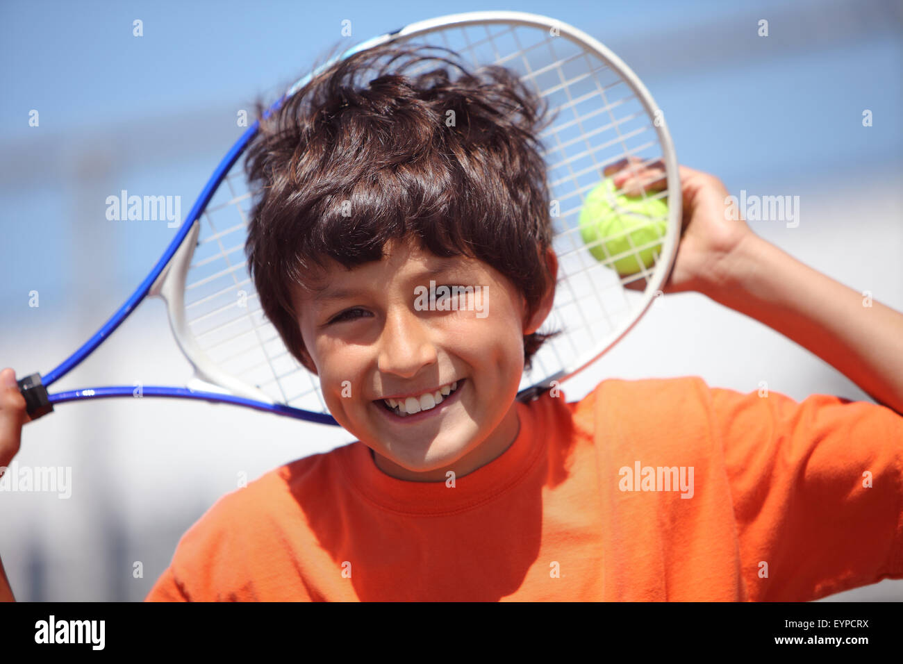 Young happy smiling boy outside in sun with tennis racket and ball ...