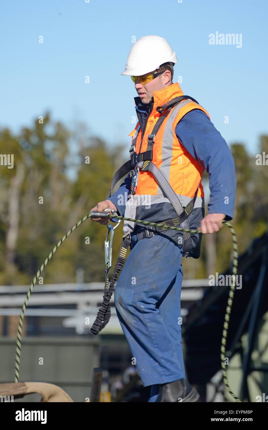 A builder wears a safety harness while working at heights on a ...
