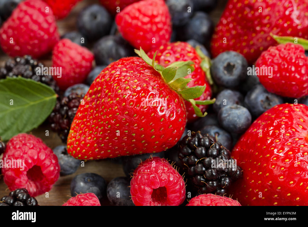 Close up of fresh berries, focus on center strawberry, in filled frame ...