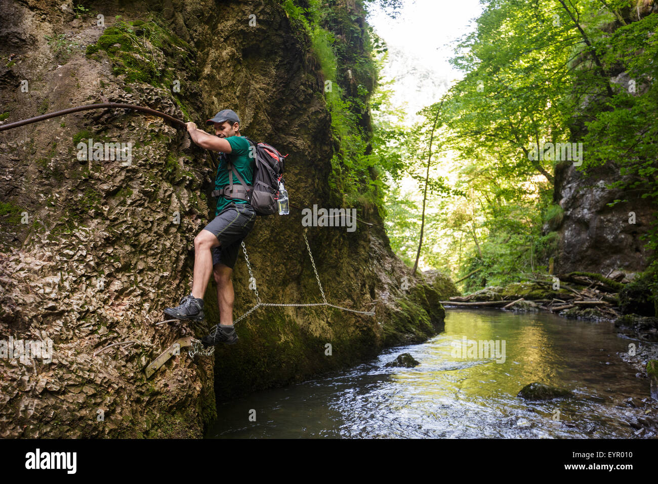 Man hiker climbing on safety cables in a gorge above the river Stock ...