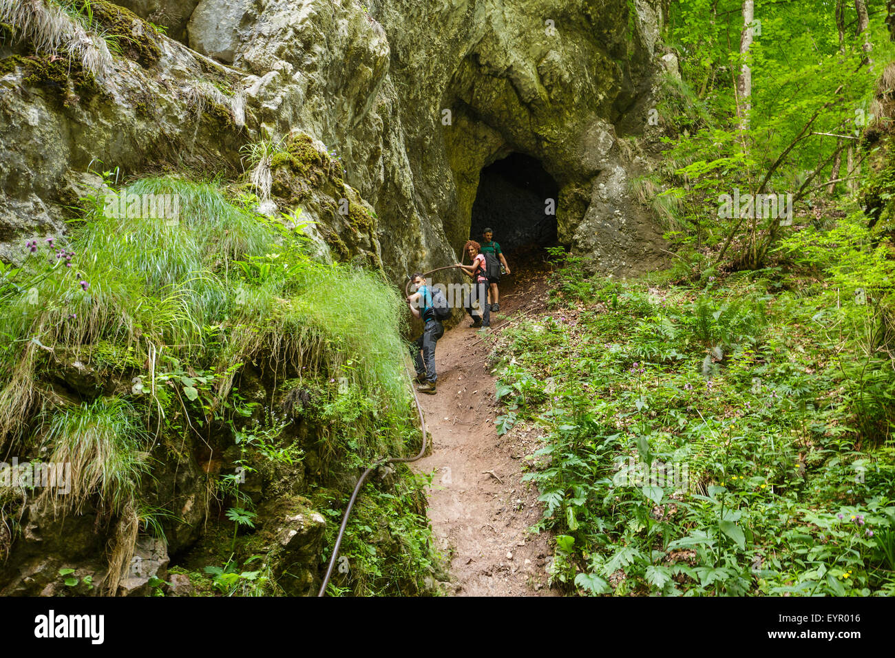 Family of hikers getting out from a cave holding on to a safety cable ...