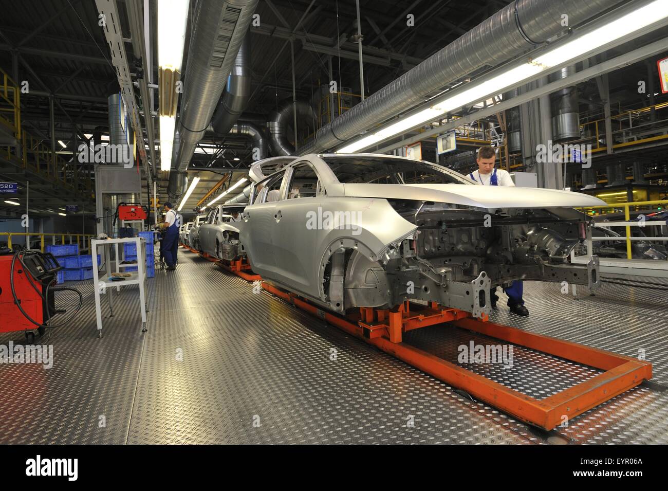 Inside a modern car factory, vehicles and parts move through the ...