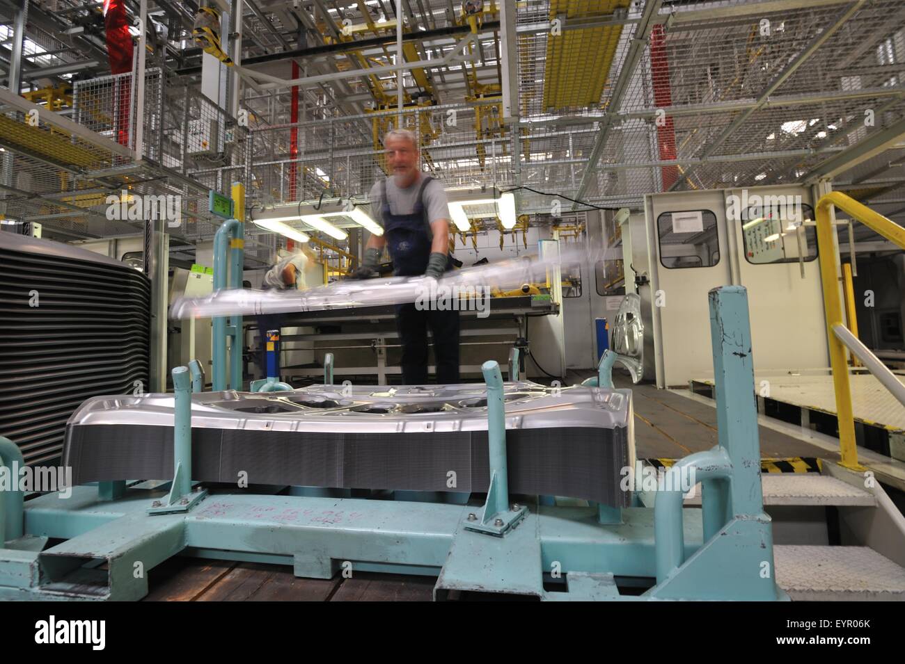 Inside a modern car factory, vehicles and parts move through the ...