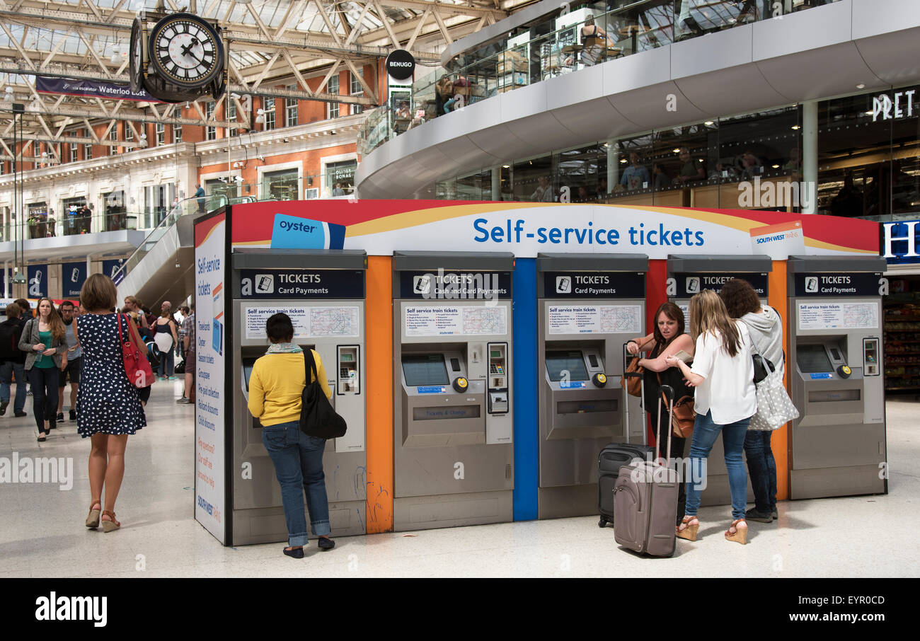 Rail travellers purchasing railway tickets from a self service machine ...