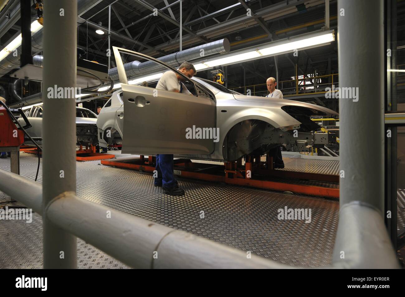 Inside a modern car factory, vehicles and parts move through the ...