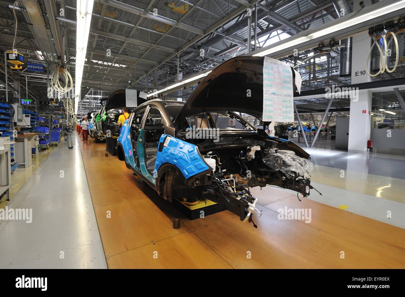 Inside a modern car factory, vehicles and parts move through the ...