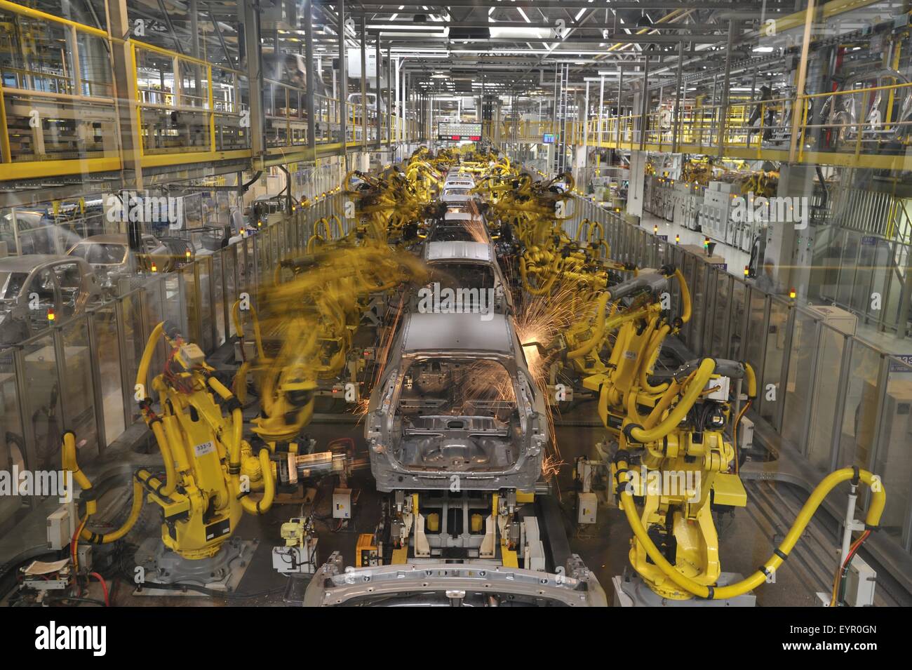 Inside a modern car factory, vehicles and parts move through the ...