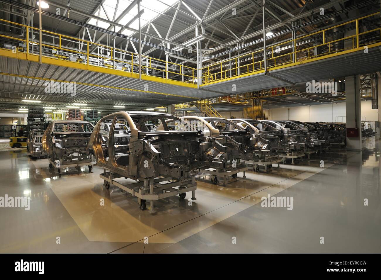 Inside a modern car factory, vehicles and parts move through the ...