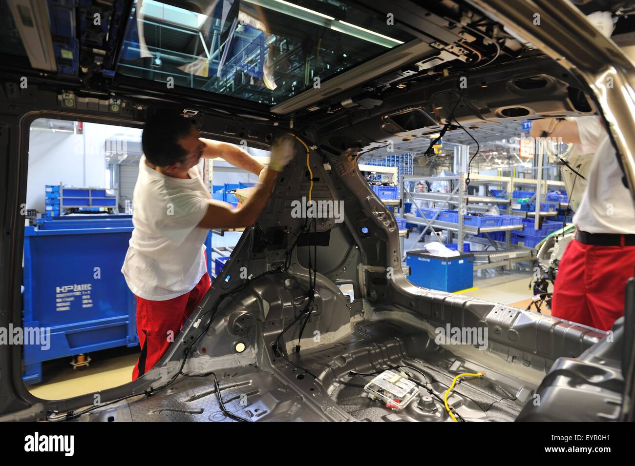 Inside a modern car factory, vehicles and parts move through the ...