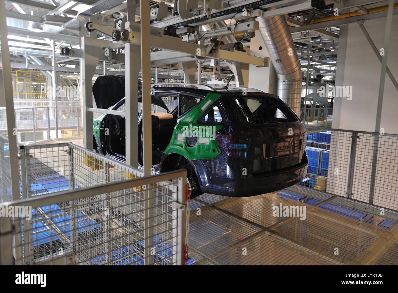 Inside a modern car factory, vehicles and parts move through the ...