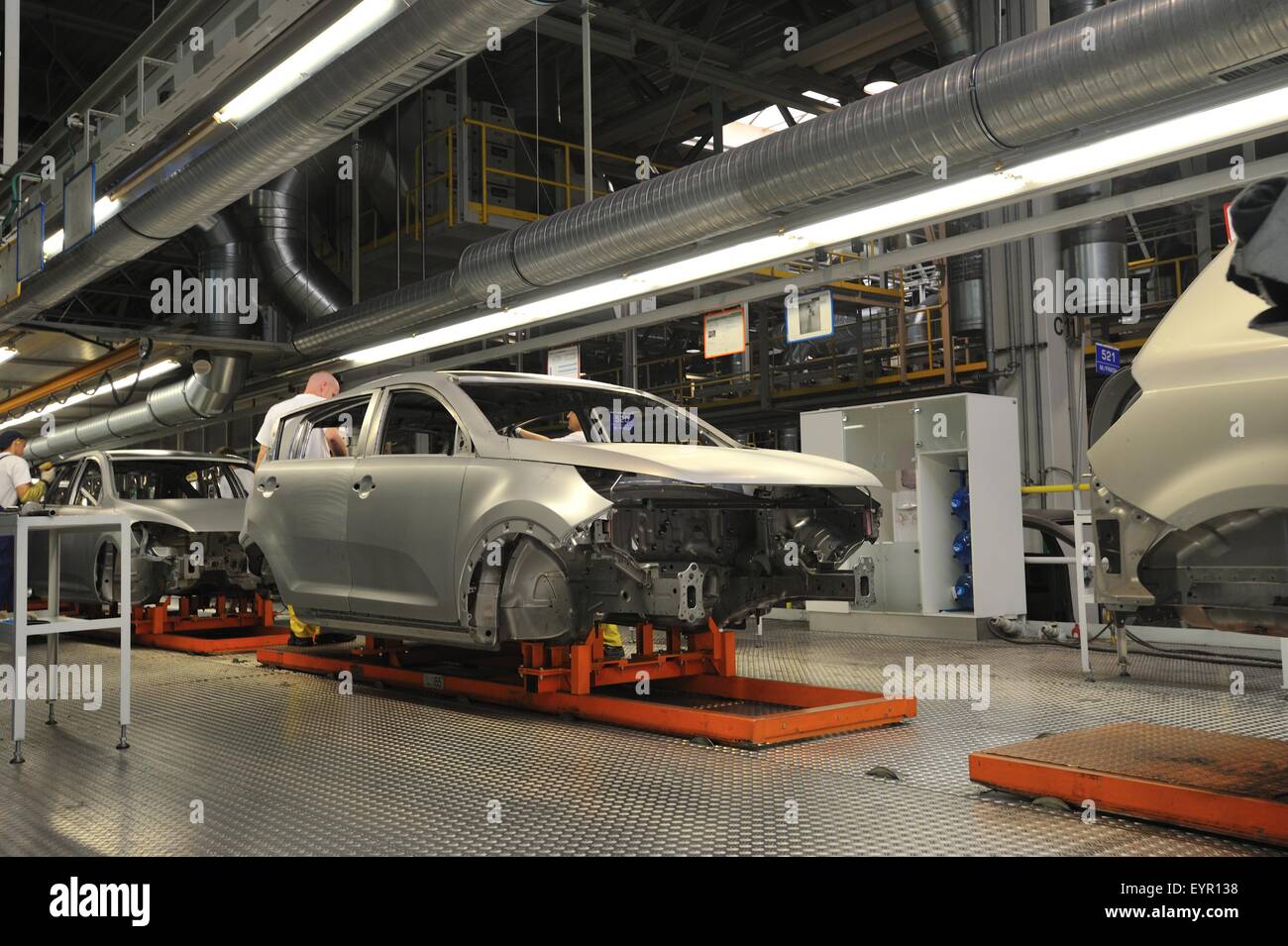 Inside a modern car factory, vehicles and parts move through the ...