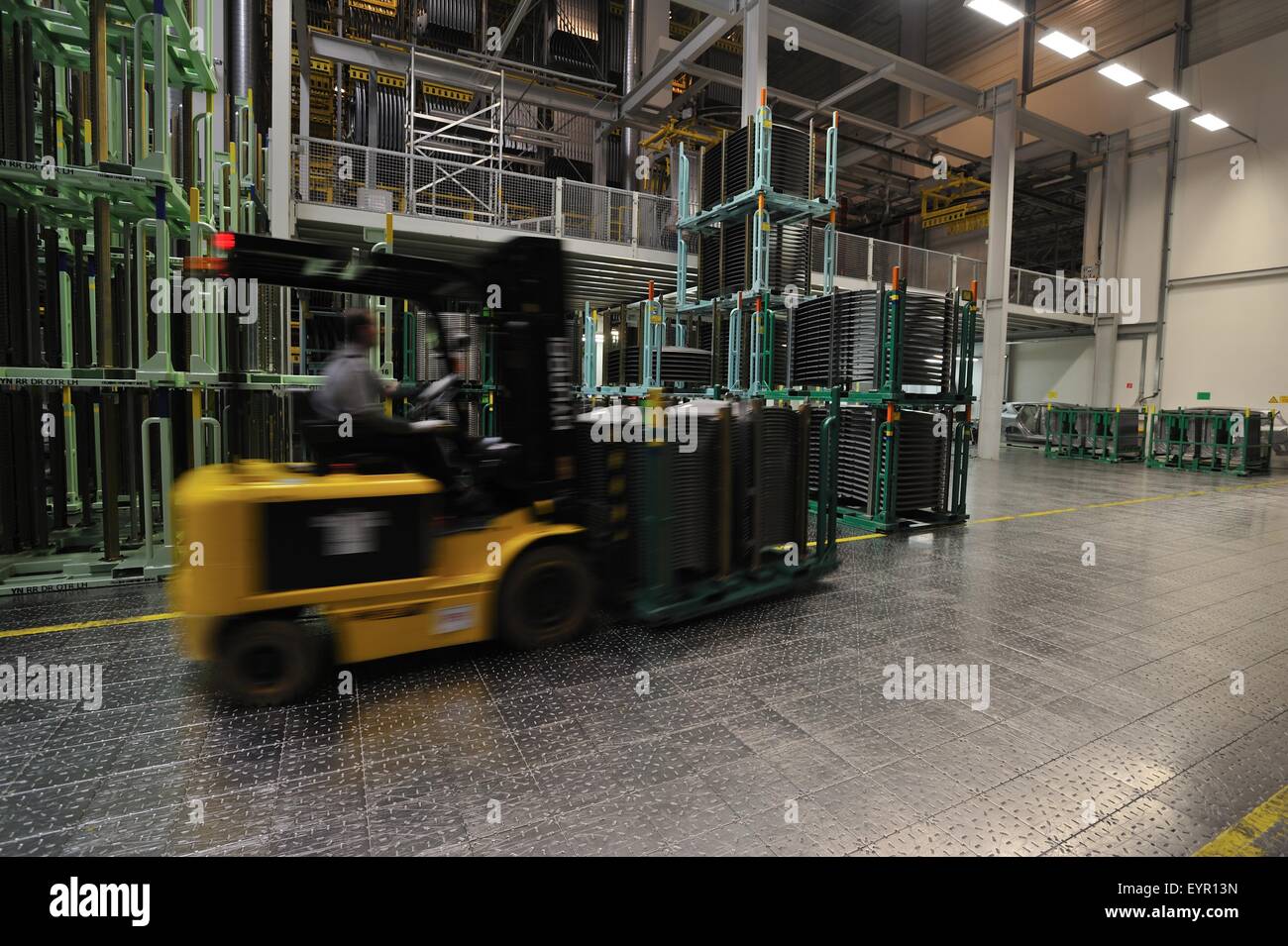 Inside a modern car factory, vehicles and parts move through the ...