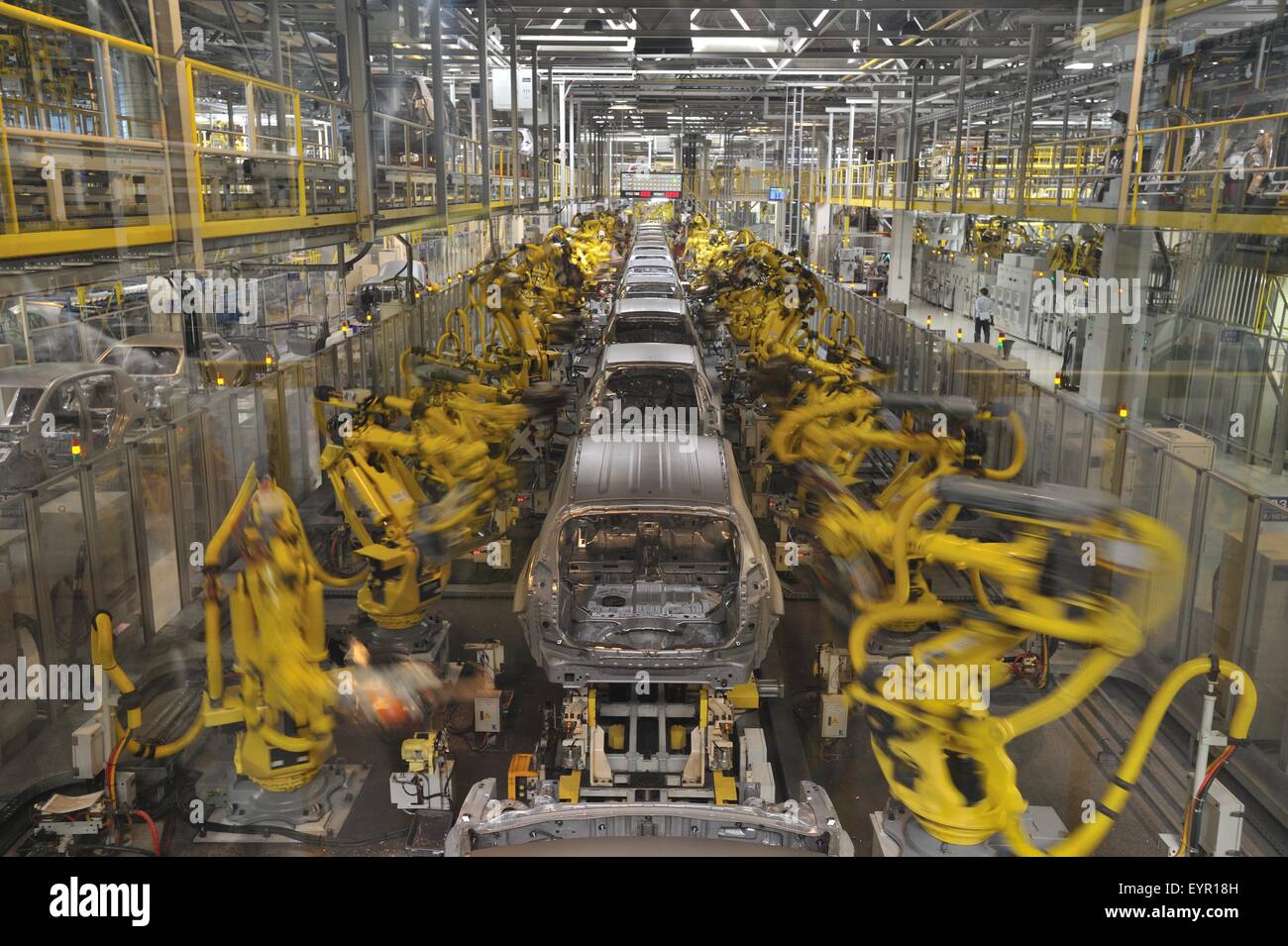 Inside a modern car factory, vehicles and parts move through the ...
