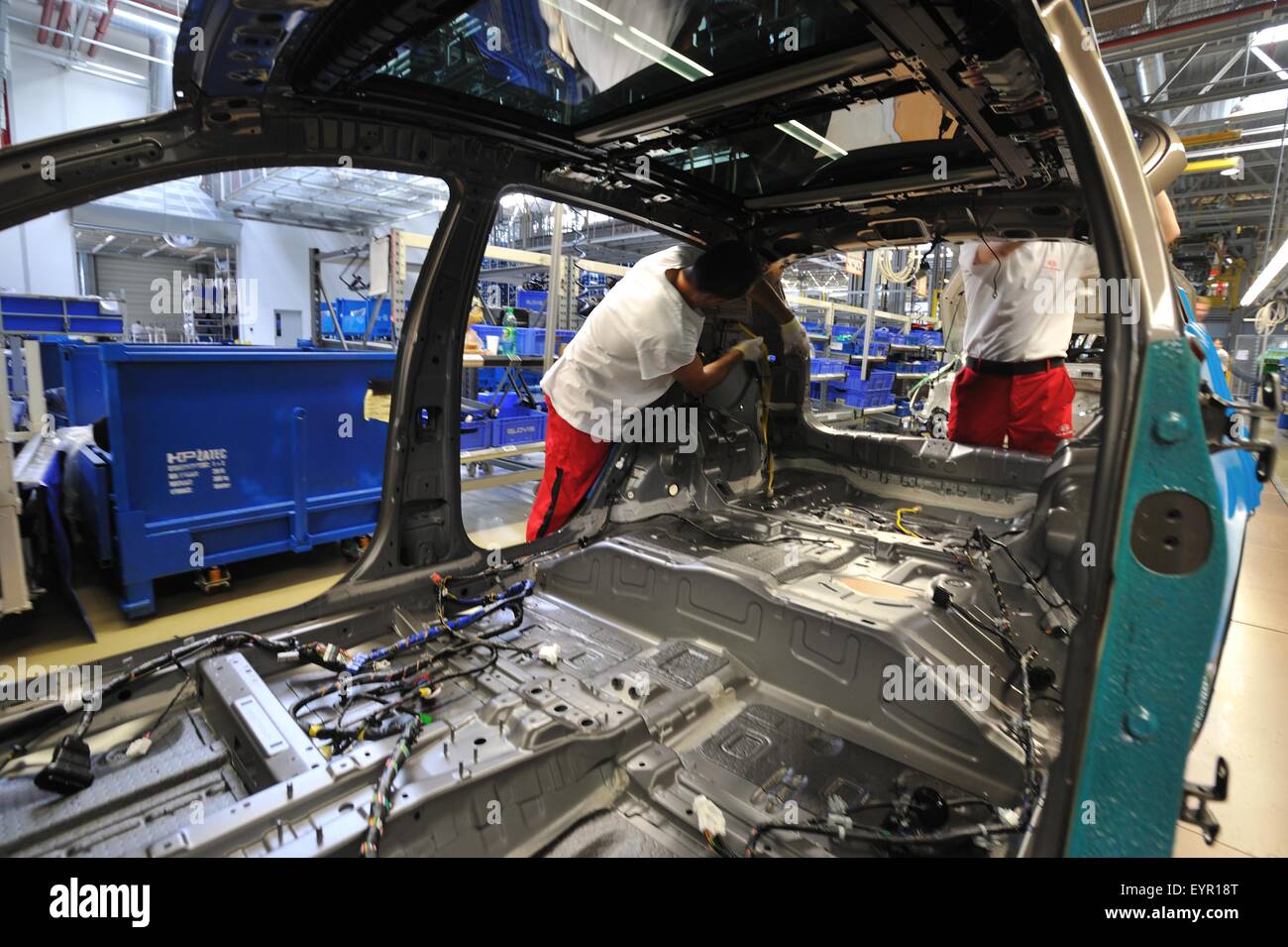 Inside a modern car factory, vehicles and parts move through the ...