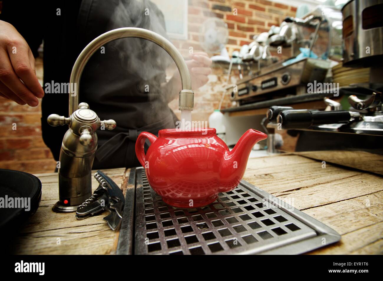 Blue traditional English tea pot being filled with steaming boiling ...