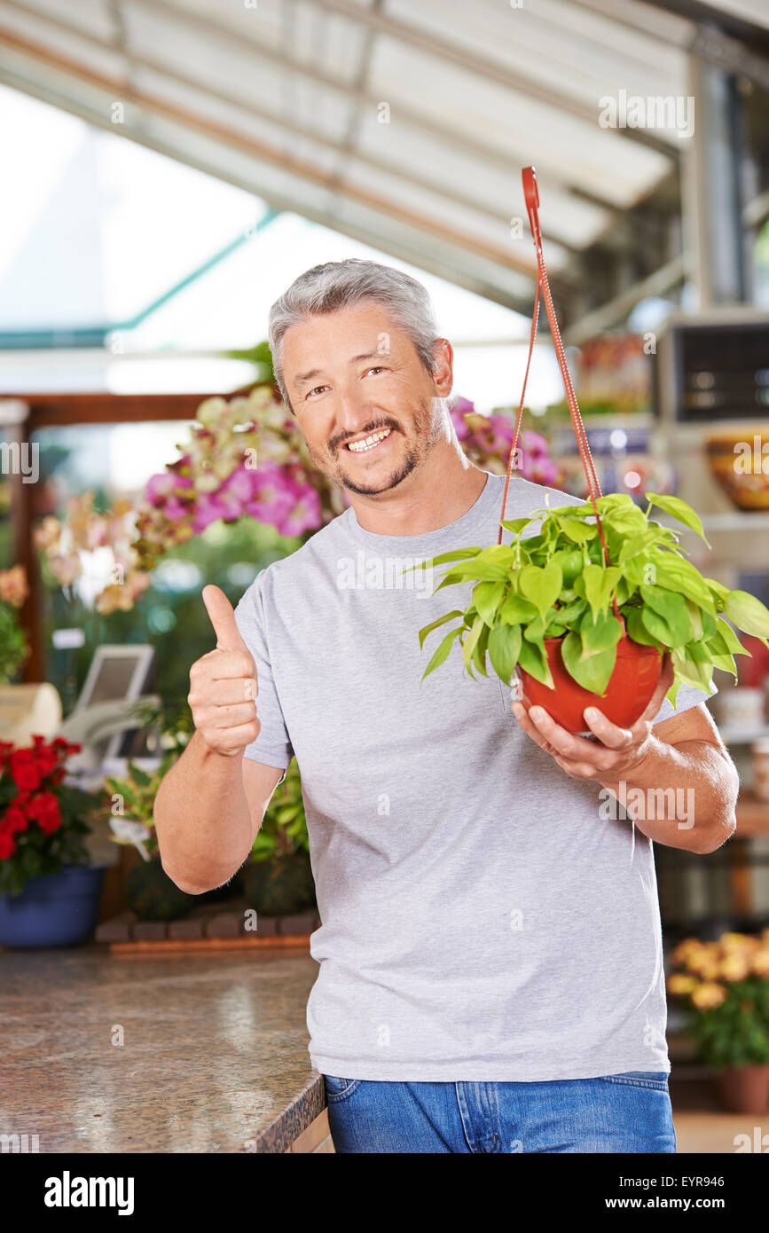 Happy gardener in garden center with plant (philodendron cordatum ...