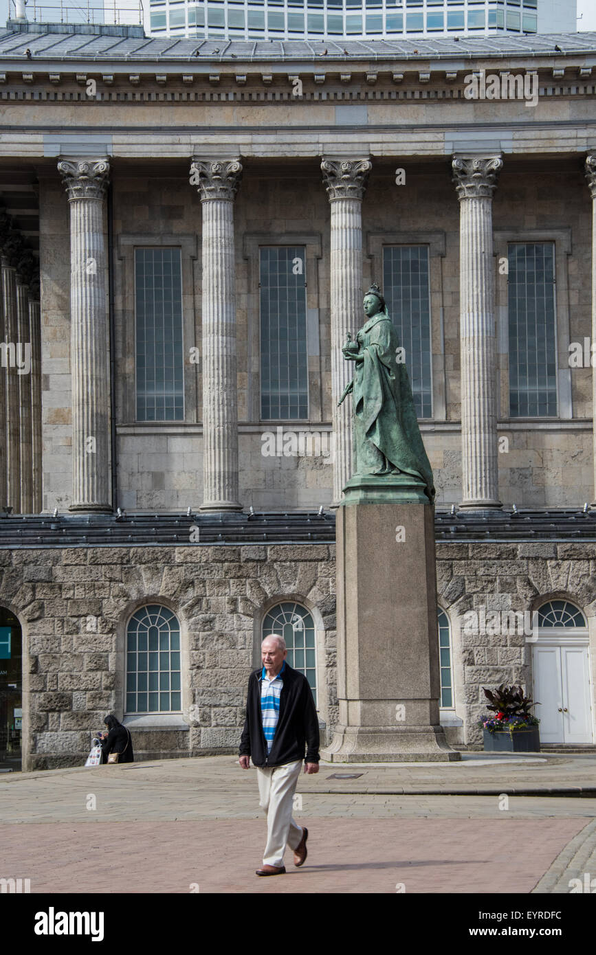 Man walking through Victoria Square past statue of Queen Victoria in ...