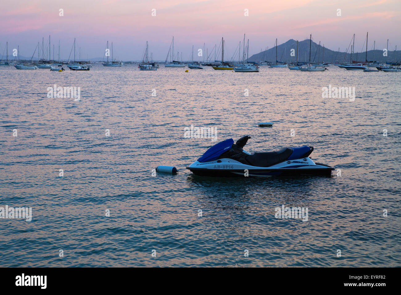 A Jet Ski parked in the water for the evening with boats, masts ...