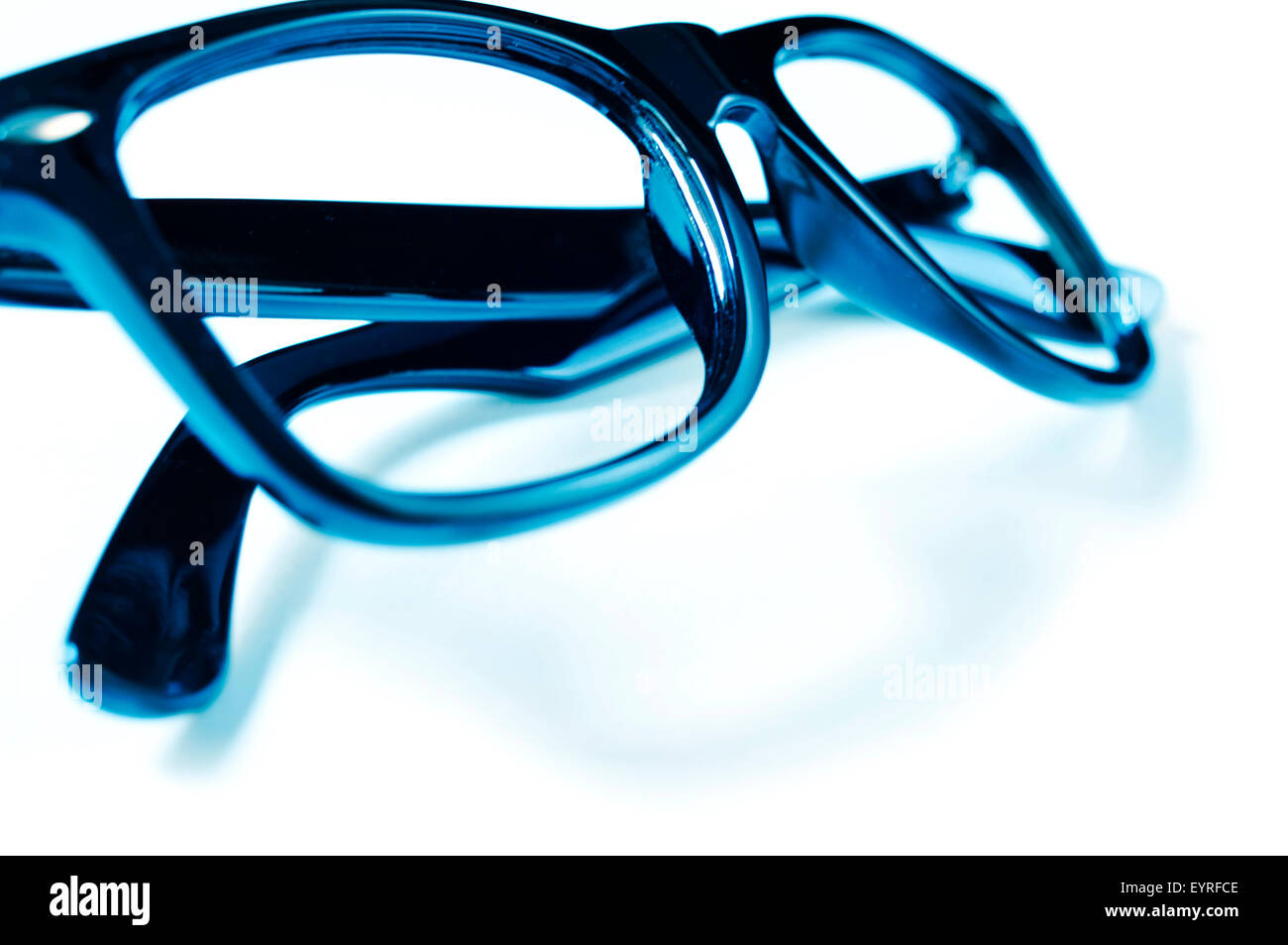 closeup of a pair of black plastic-rimmed eyeglasses on a white surface ...