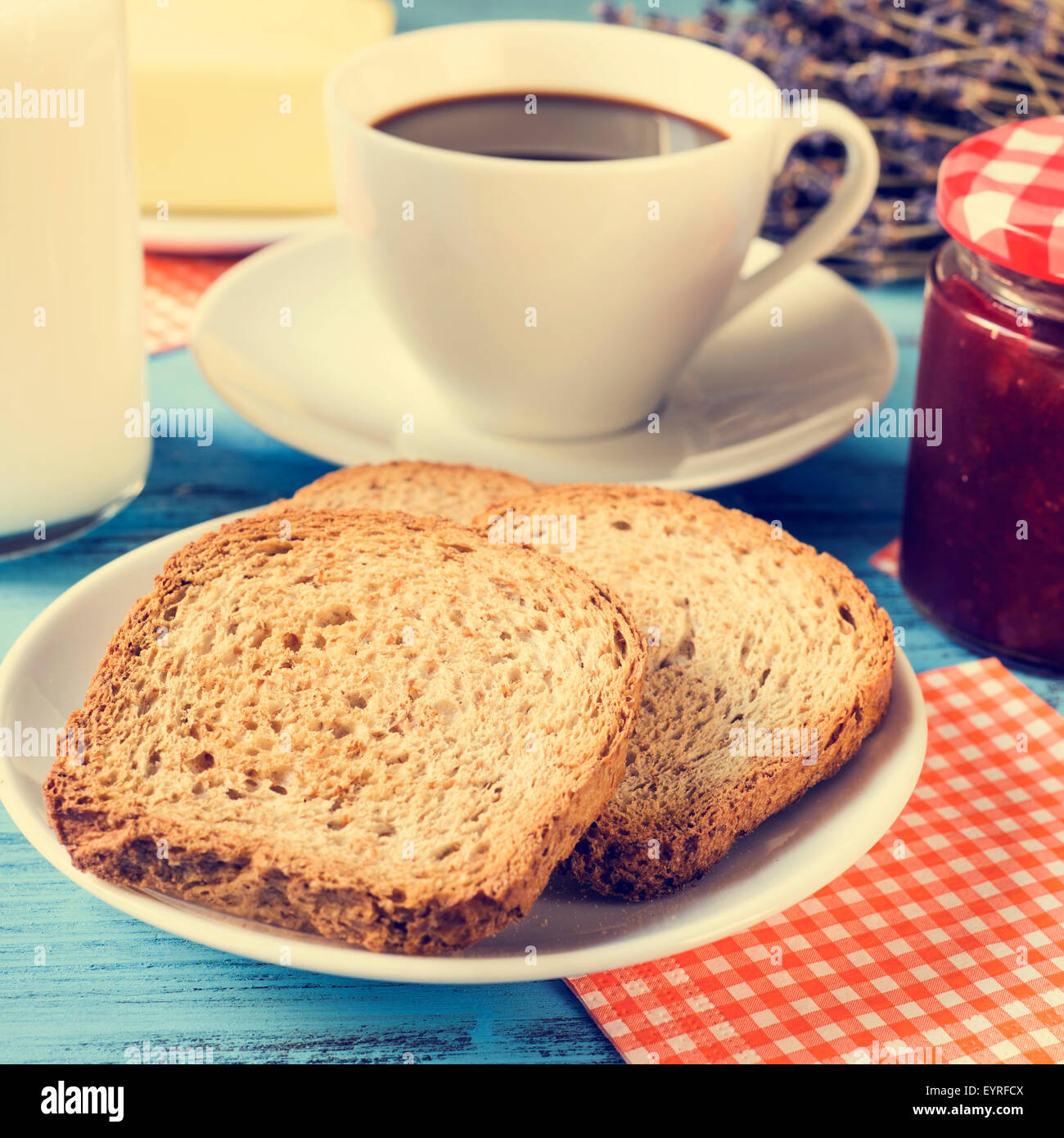closeup of some toasts in a plate, a cup of coffee, a bottle with milk ...