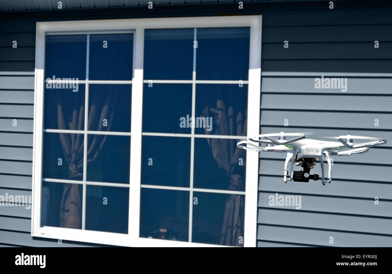 White drone with camera hovering by private house window Stock Photo ...