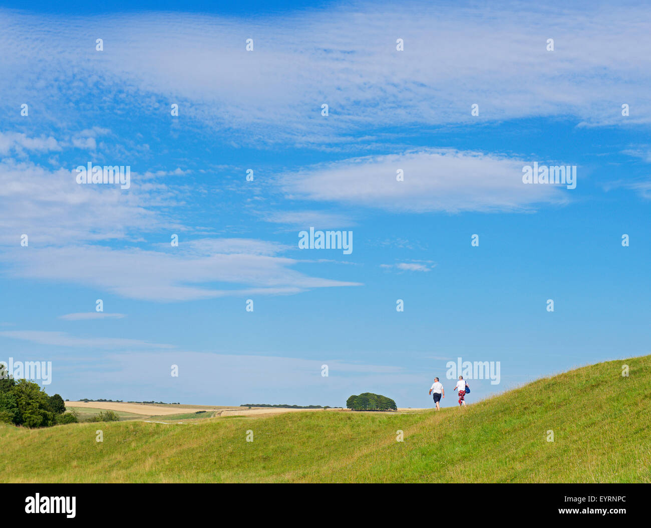 Two people walking along a ridge at Avebury, Wiltshire, England UK ...