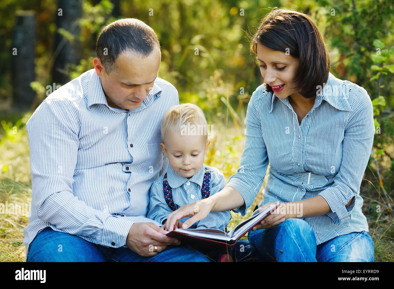 family reading book in park Stock Photo - Alamy
