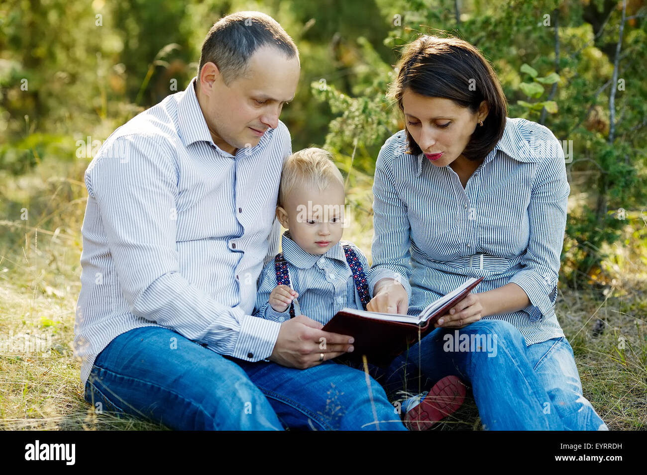 family reading book in park Stock Photo - Alamy