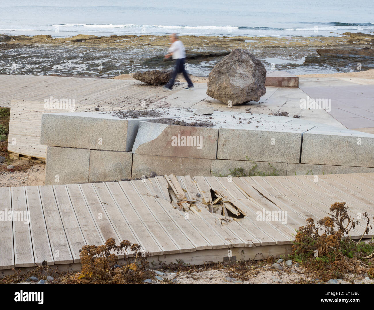 A man walks between two huge rocks which have broken away from high ...