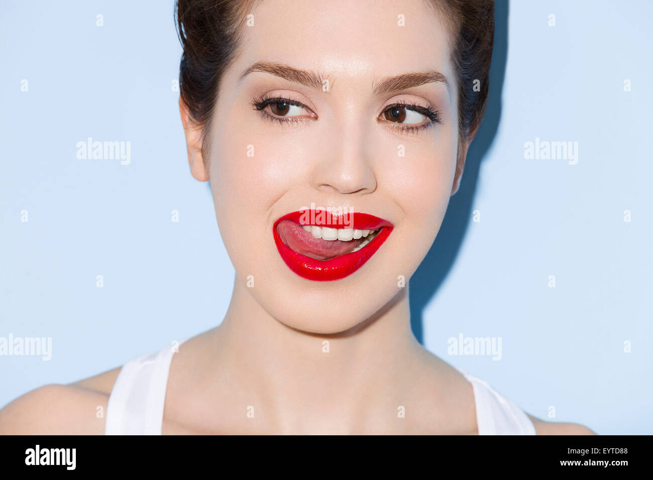 Close-up of a young woman in front of blue wall, tongue, red lips Stock ...