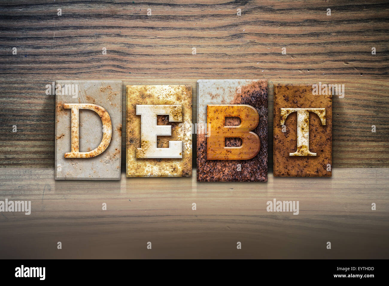 The word "DEBT" written in rusty metal letterpress type sitting on a ...