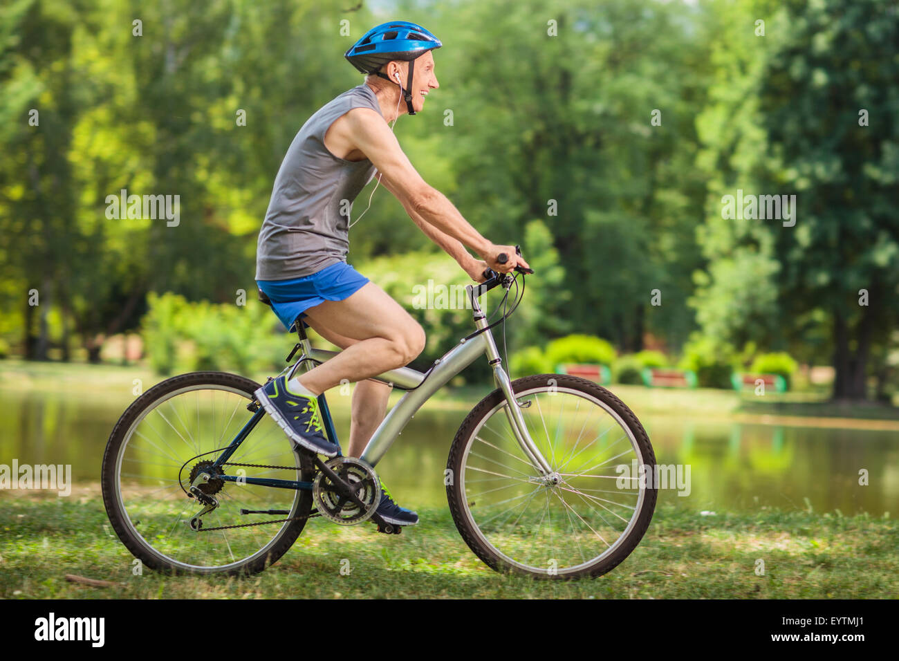 Profile shot of a joyful senior biker riding a bicycle in a park by a ...