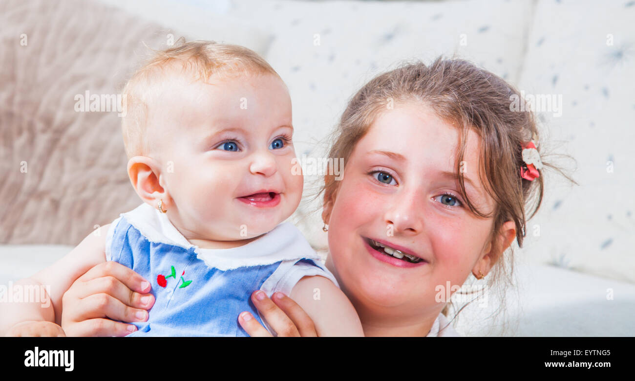 Big sister holding her 1 year old baby sister Stock Photo - Alamy