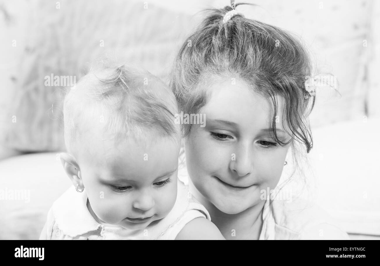 Big sister holding her 1 year old baby sister Stock Photo - Alamy