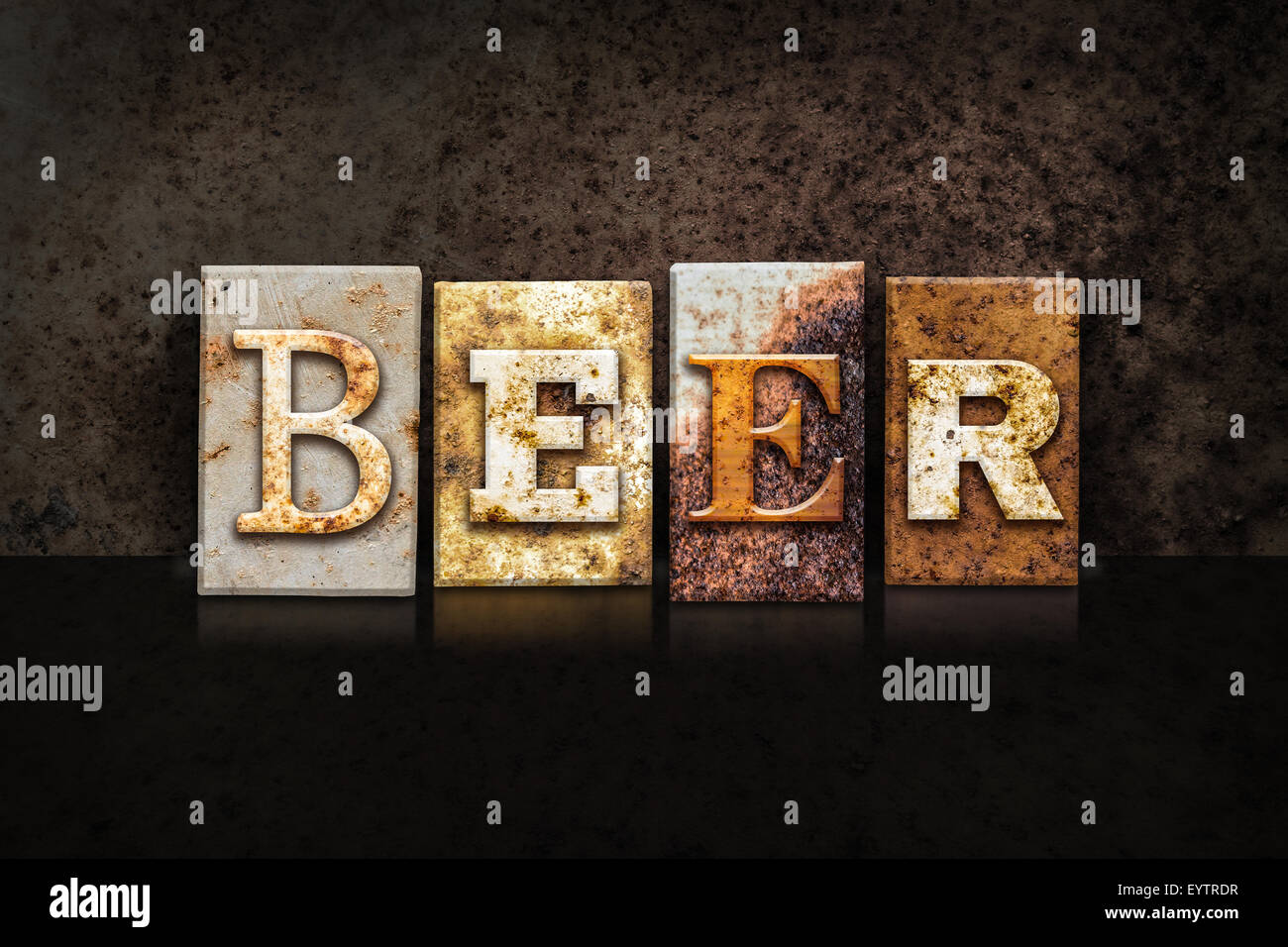 The word "BEER" written in rusty metal letterpress type on a dark ...