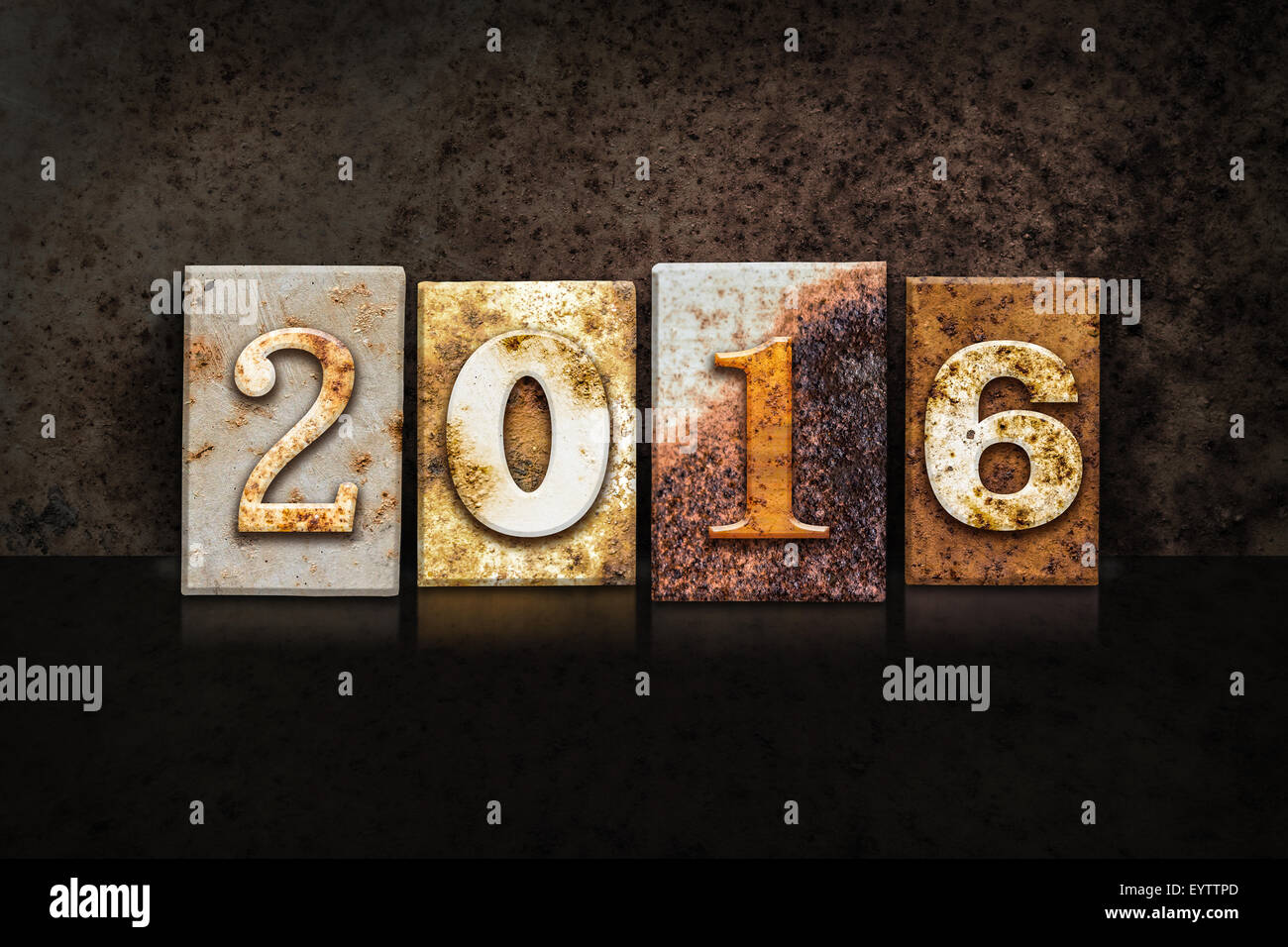 The word "2016" written in rusty metal letterpress type on a dark ...