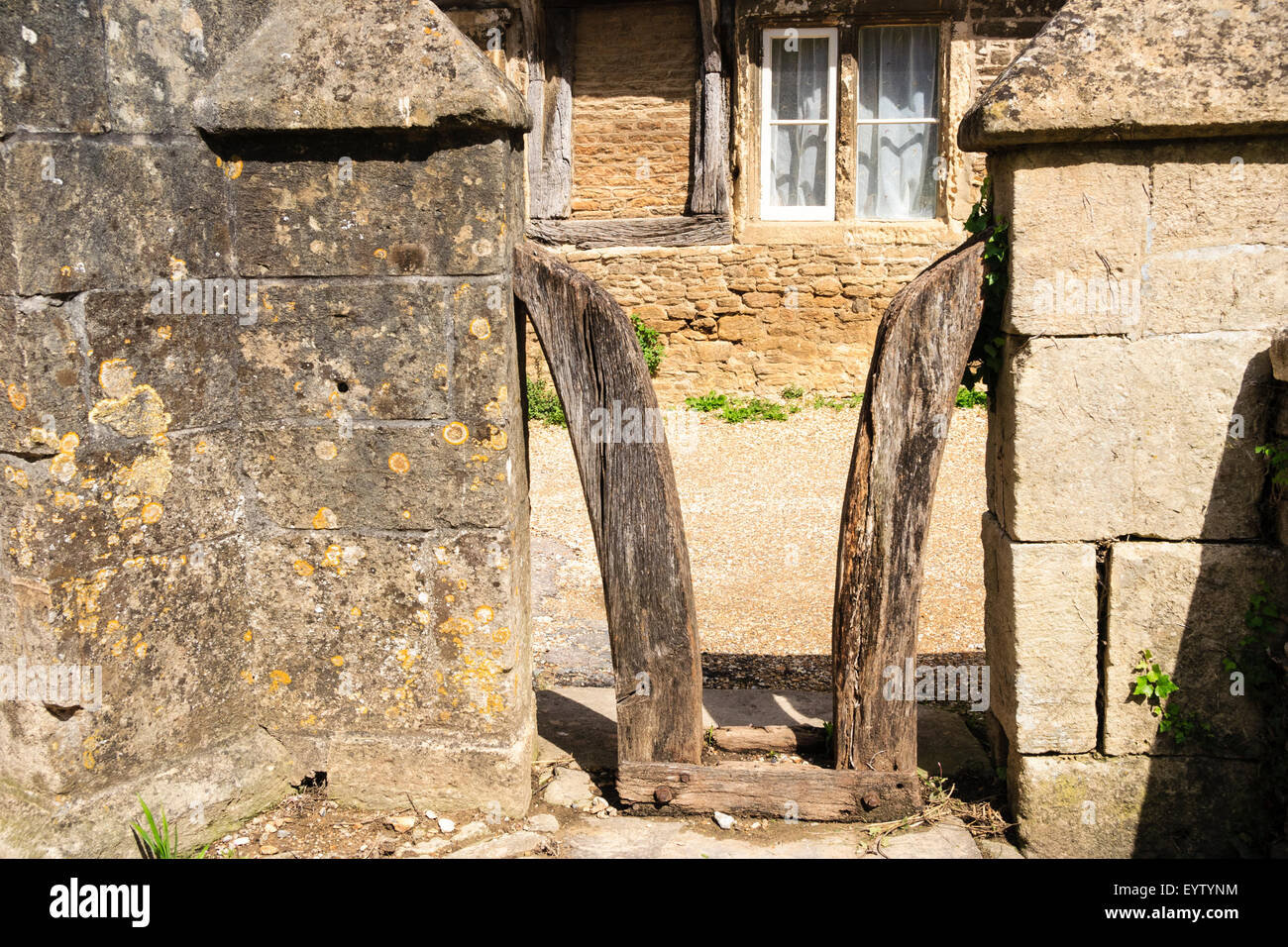 England, Lacock, Cotswold. Stone wall with old timber sheep-gate ...