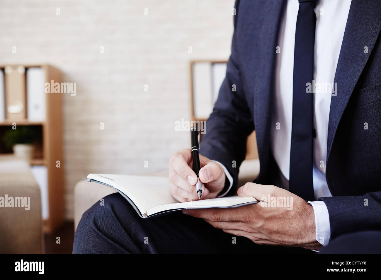 Male employee with pen and notepad writing plan Stock Photo - Alamy