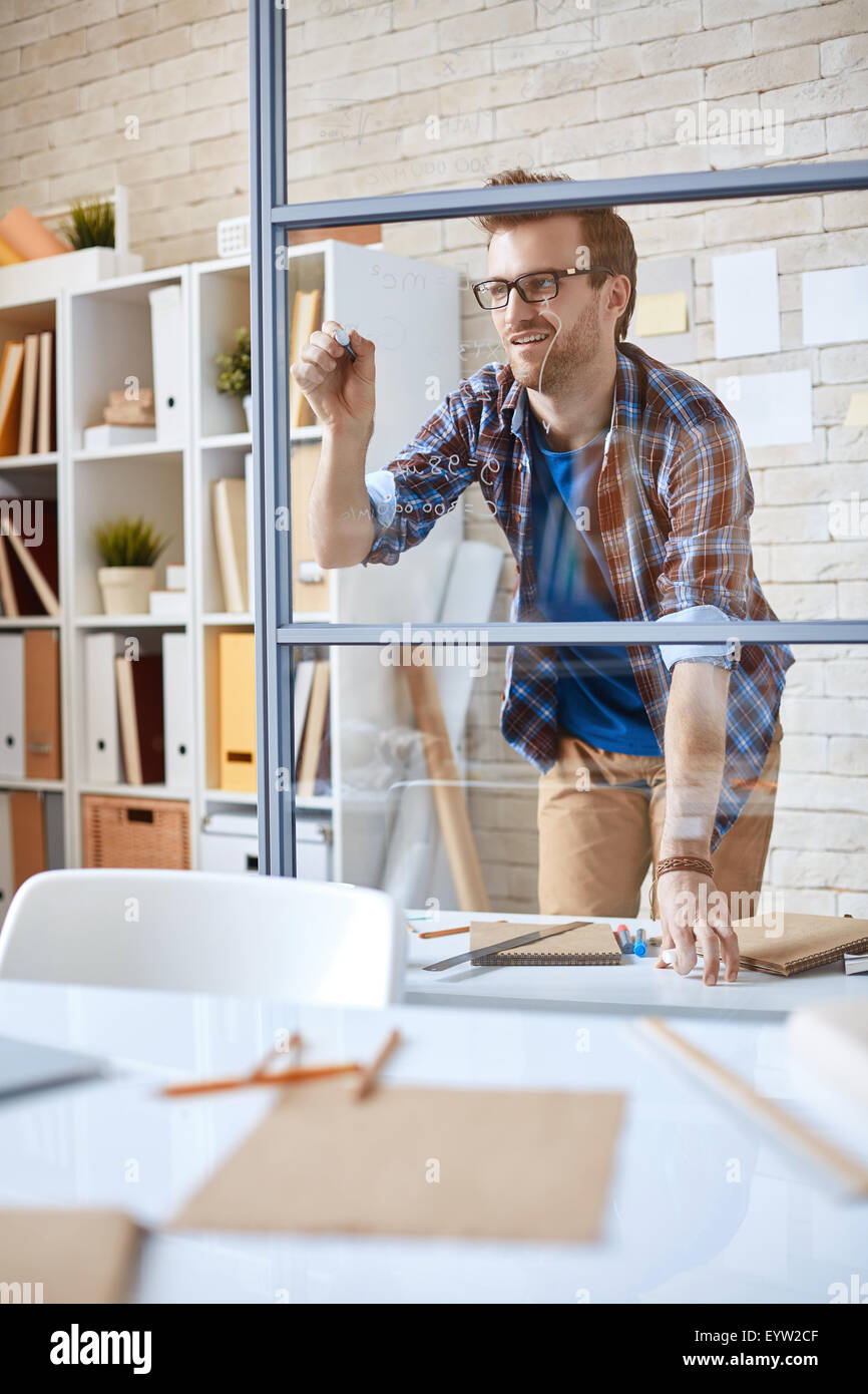Handsome employee reviewing data in graph on transparent board in ...