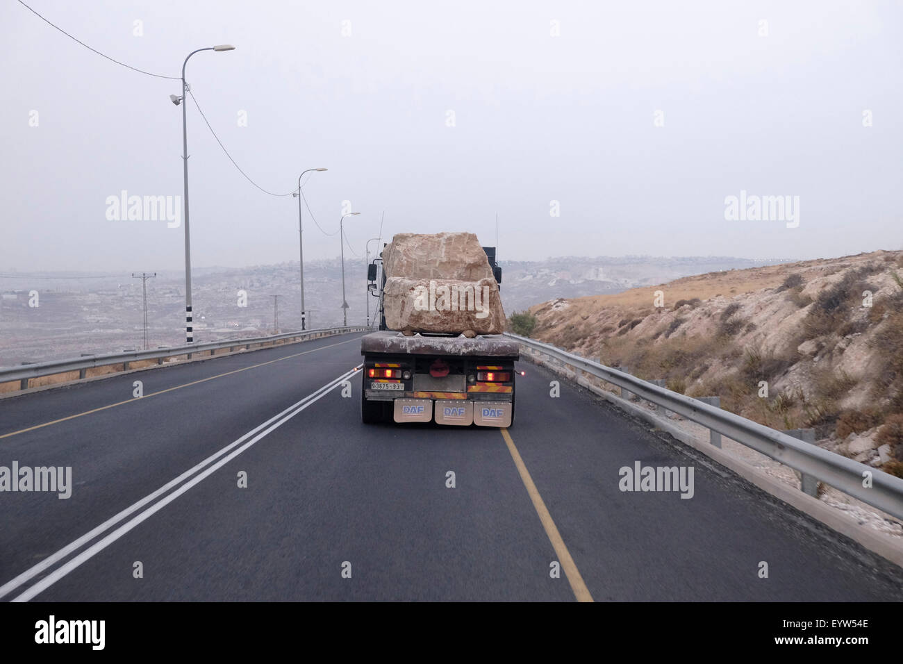 A truck loaded with a huge limestone rock driving through Highway 60 in ...