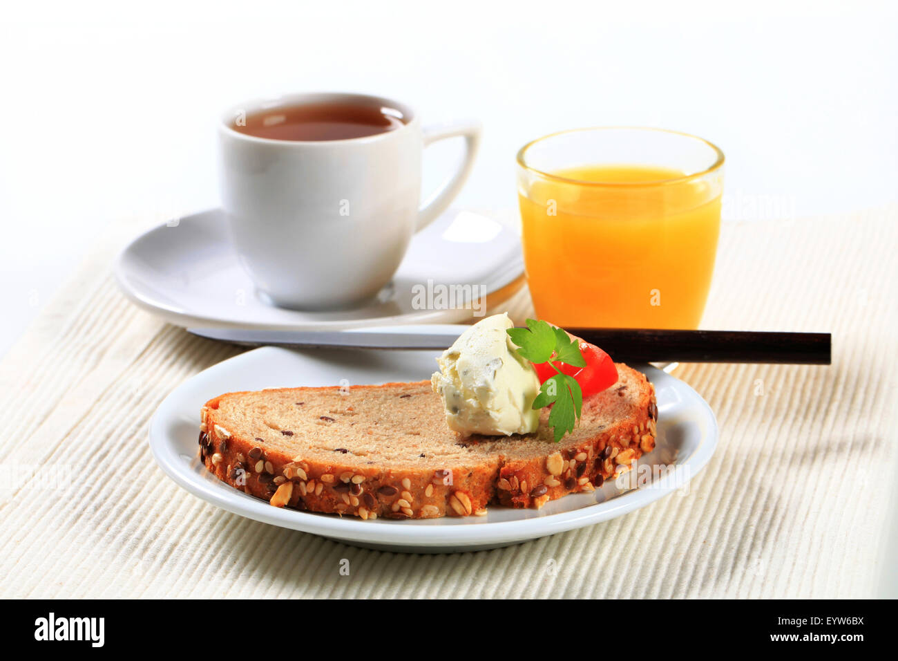 Still life of bread with cheese spread, cup of tea and orange juice ...