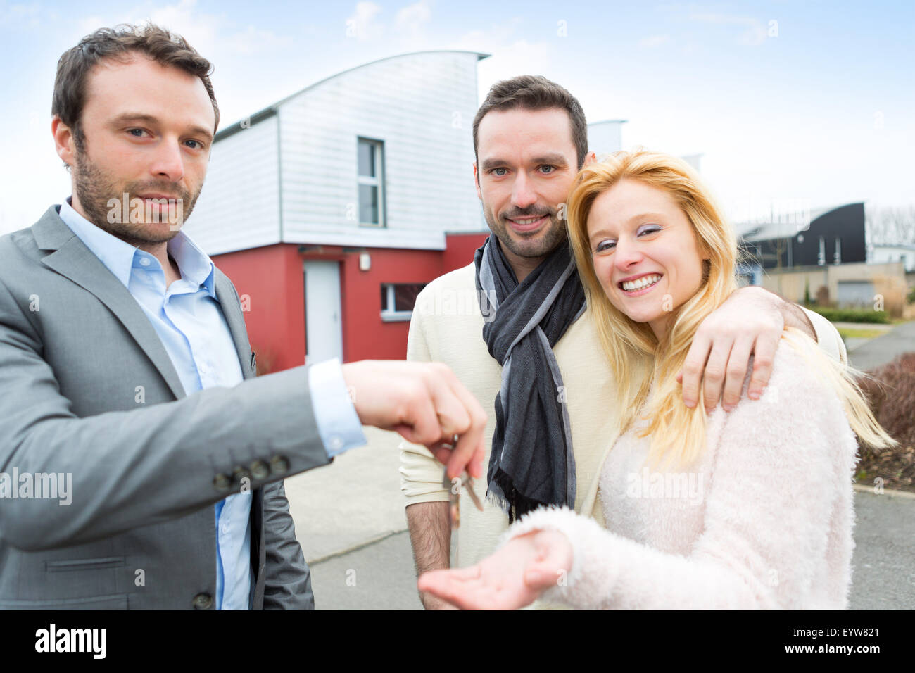 View of a Real estate agent delivers keys to young atractive couple ...