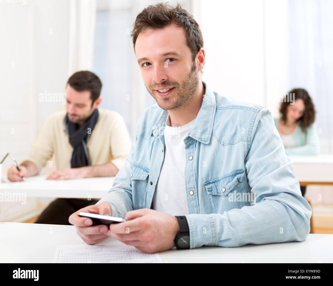 View of a Young attractive student using his mobile during classes ...