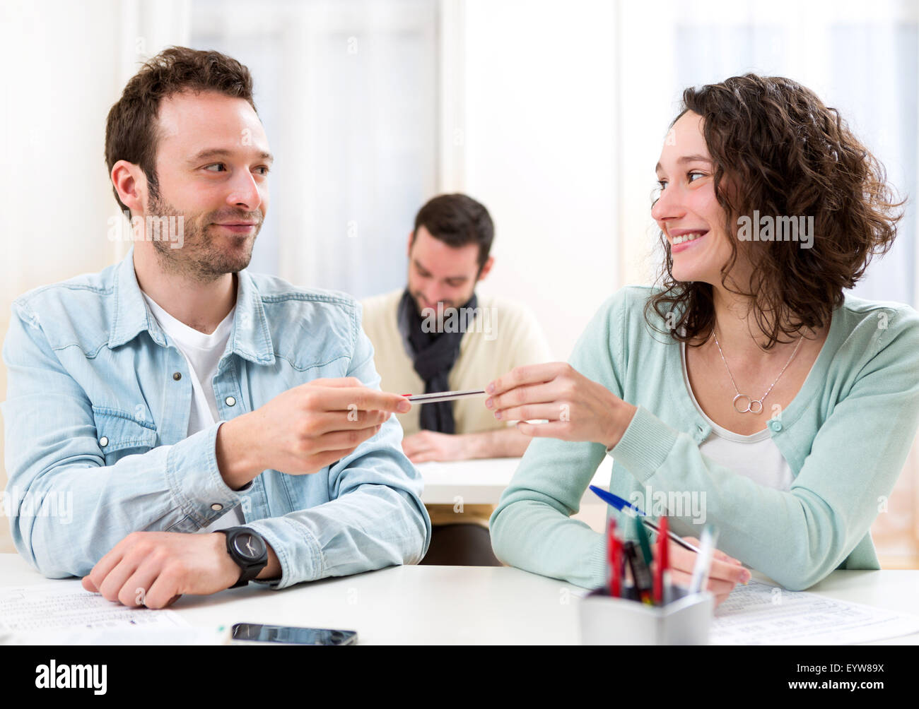 View of a Young attractive student lend a pen to classmate Stock Photo ...