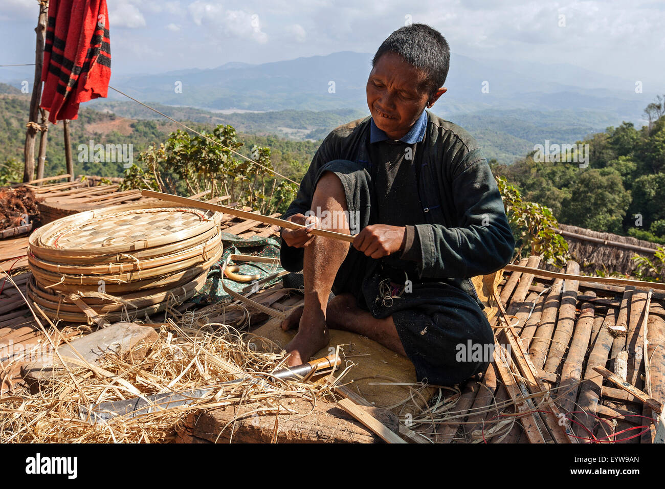 Indigenous man, Ann tribe, sitting on a bamboo terrace working on ...