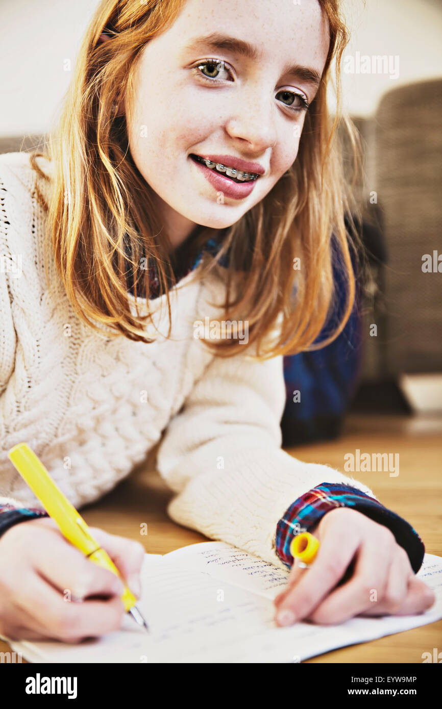 Girl doing her homework on the floor at home Stock Photo - Alamy