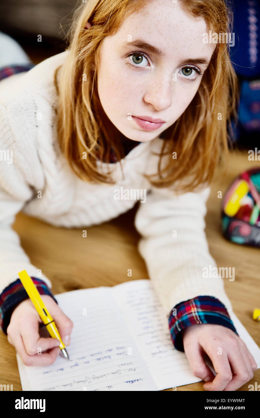 Girl doing her homework on the floor at home Stock Photo - Alamy
