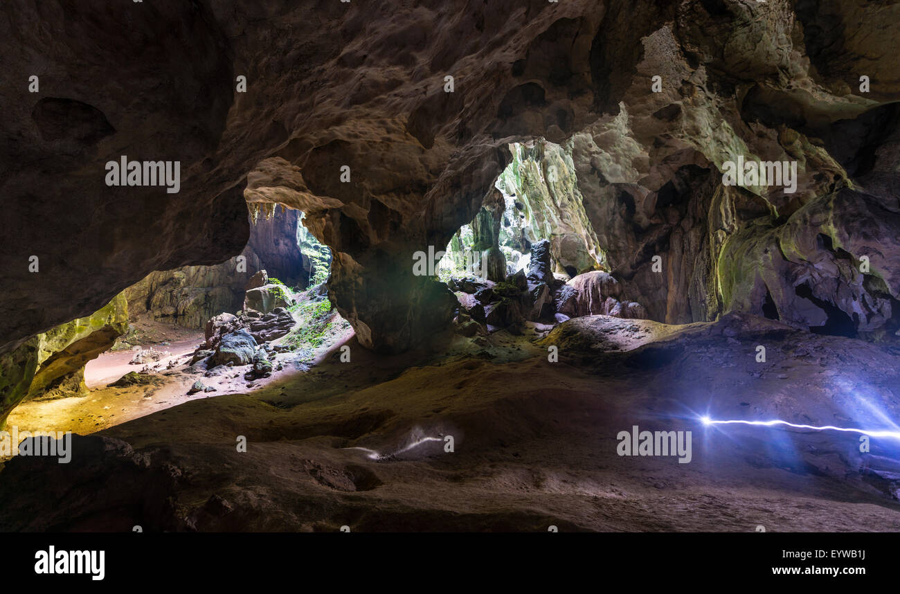 Hikers walking through a large cave, light trails, stalactite cave ...