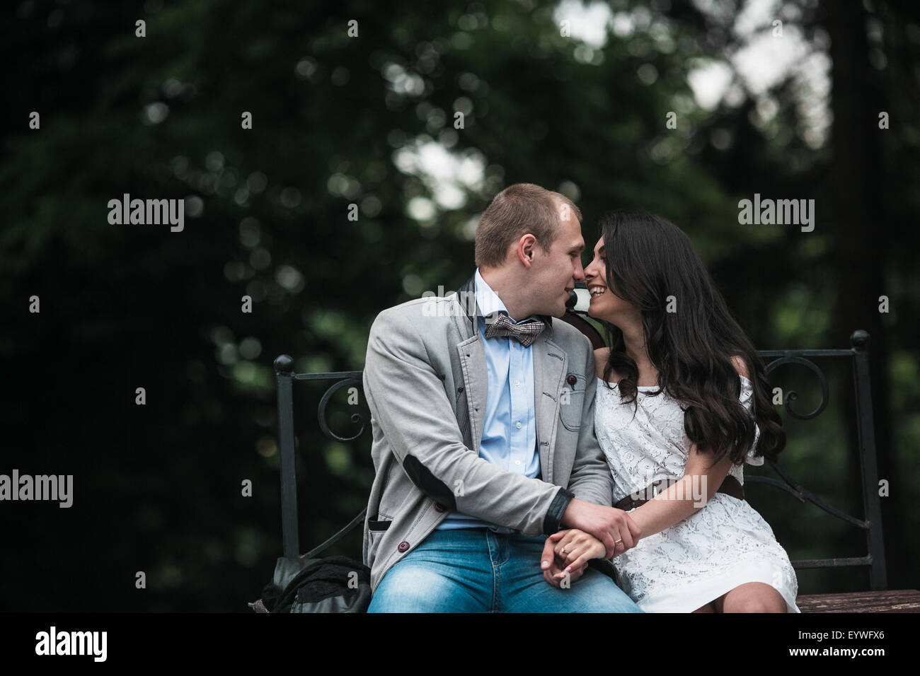 Young European couple cuddling on a park bench Stock Photo - Alamy
