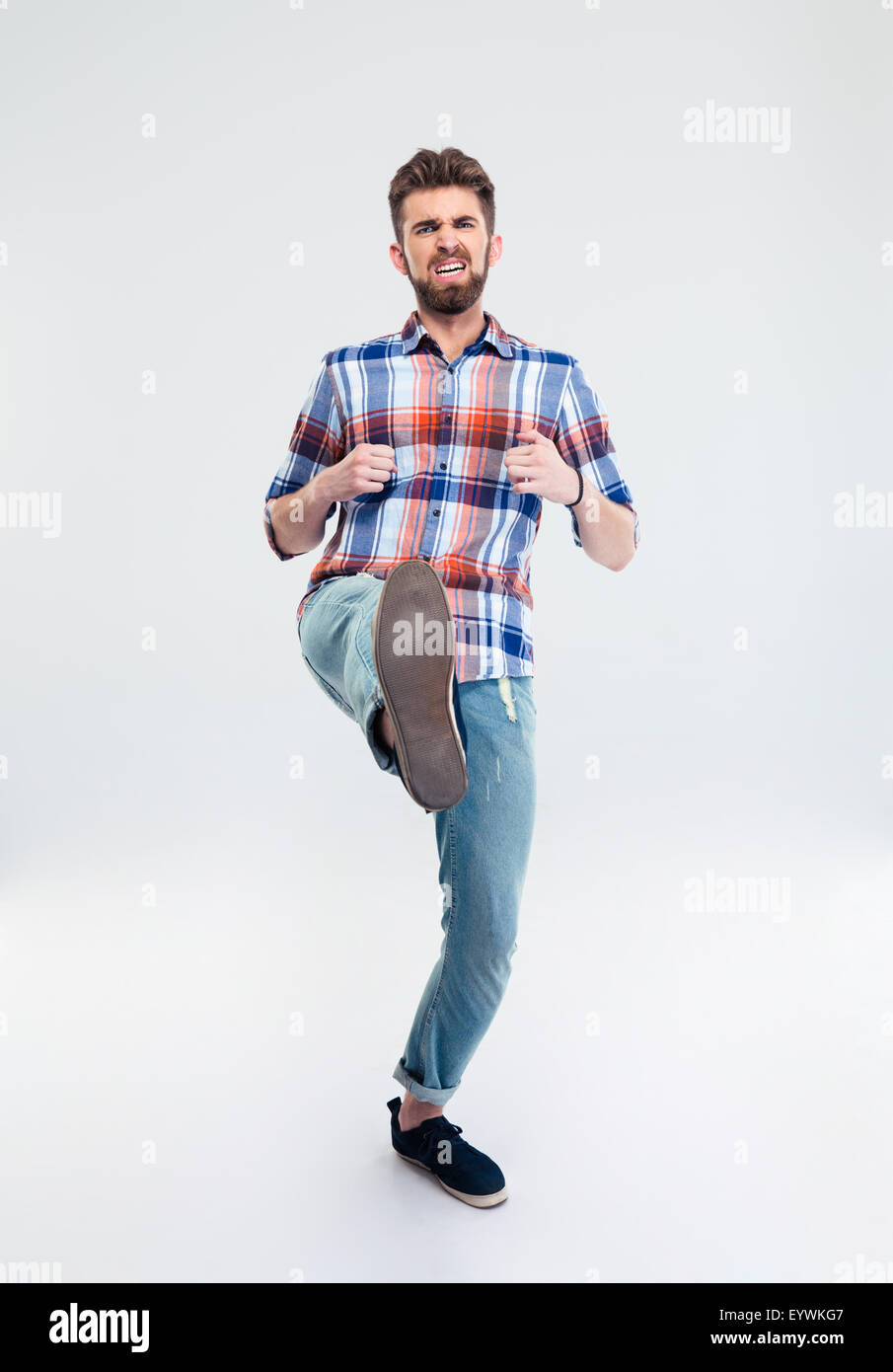 Full length portrait of angry man kicking isolated on a white ...